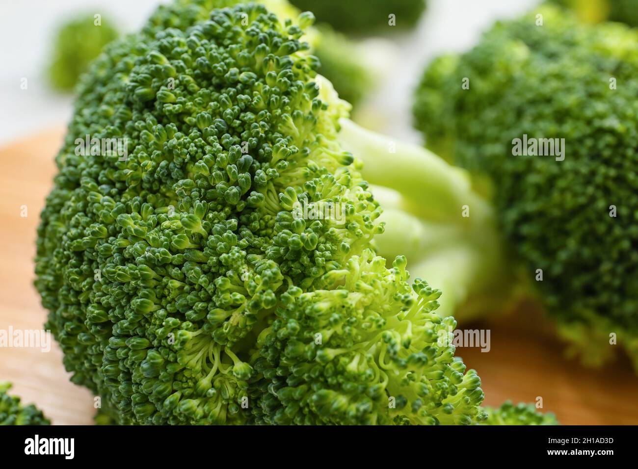Board with healthy broccoli cabbage on light wooden background, closeup ...