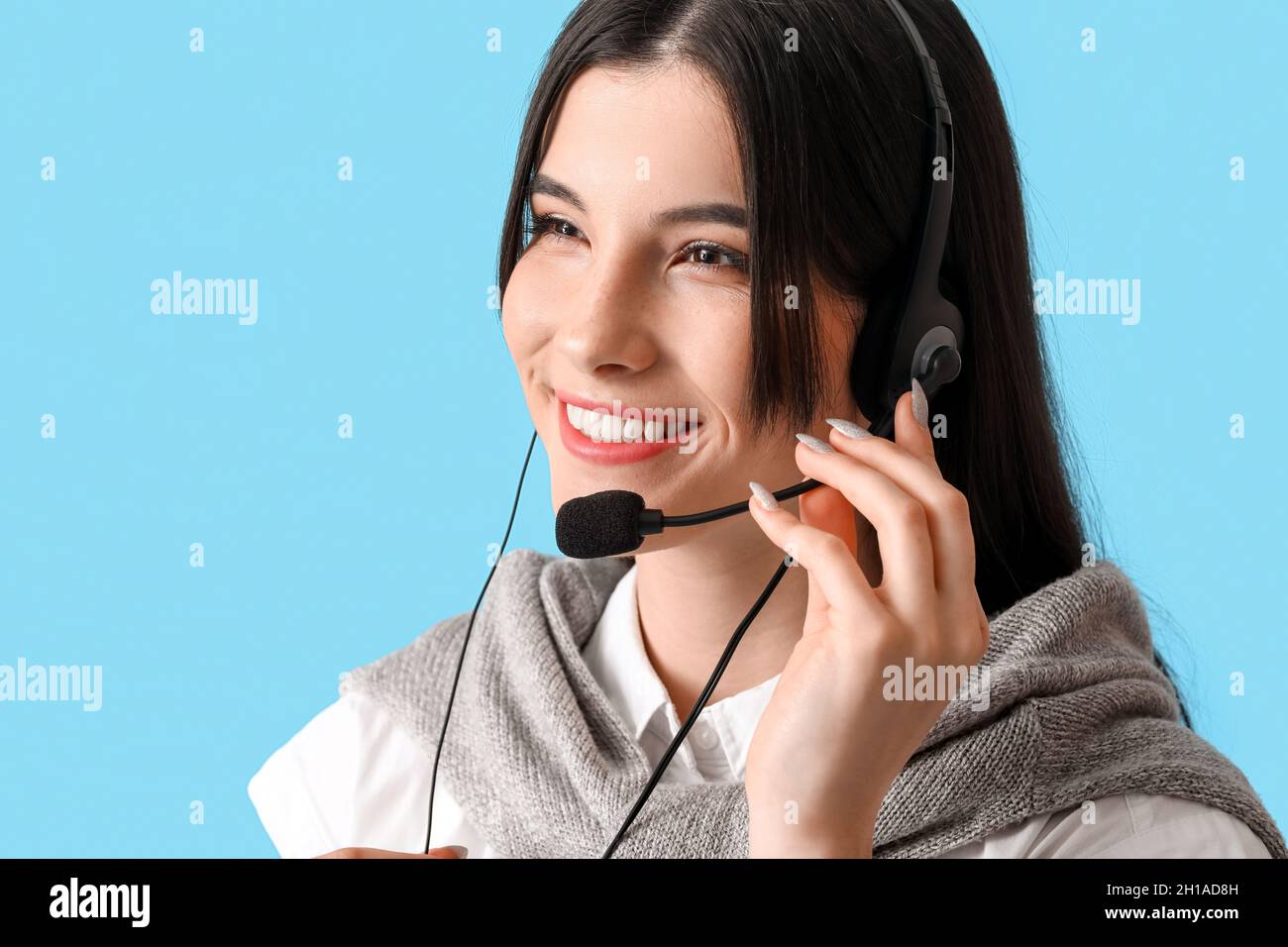 Beautiful consultant of call center in headset on blue background ...