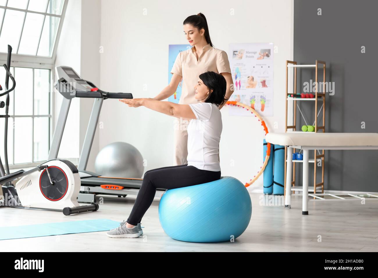 Mature woman training with fitball and physiotherapist in ...