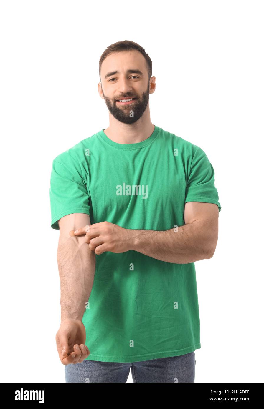 Handsome man applying adhesive patch onto his arm on white background ...