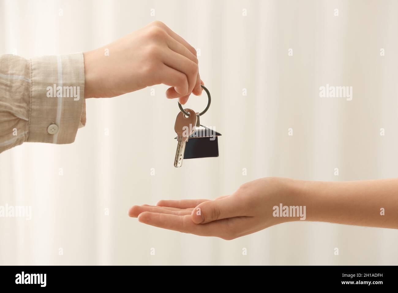 Real estate agent passing key with house shaped keychain to woman ...