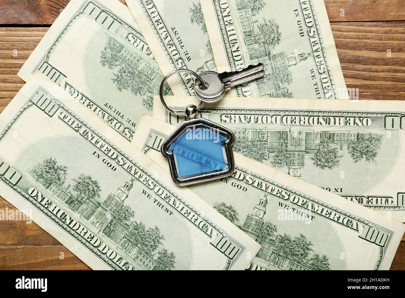 Key with house shaped keychain and money on wooden background Stock ...