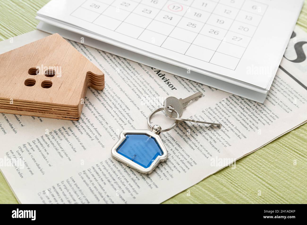 Calendar, figure of house, keys with keychain and newspaper on color ...