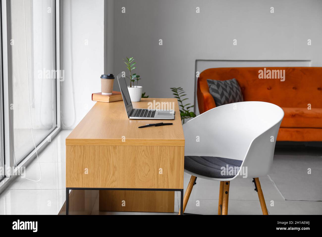 Wooden table with laptop near window in modern living room Stock Photo ...