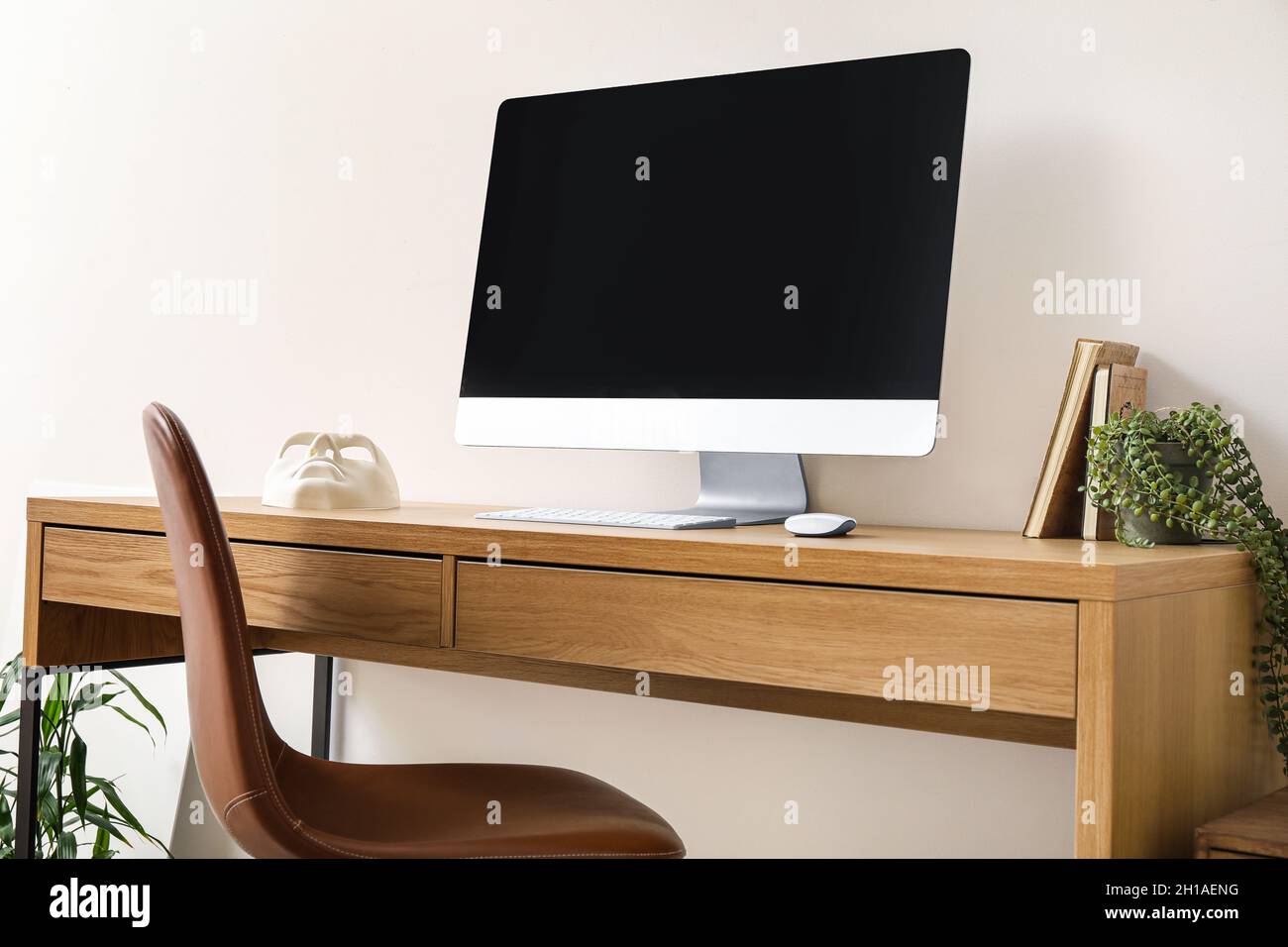 Wooden table with computer and leather chair near light wall Stock ...
