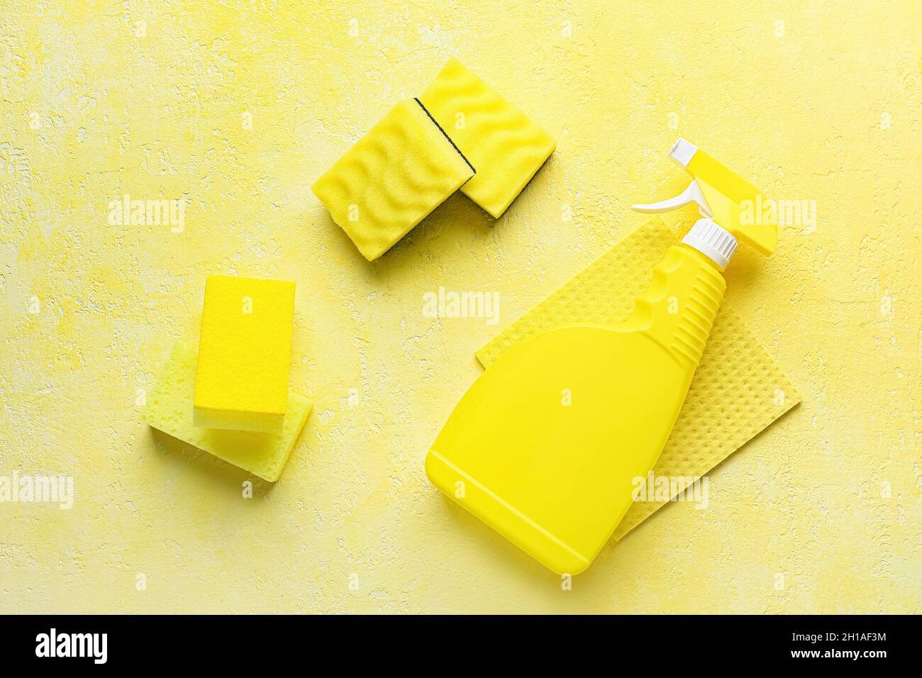 Yellow cleaning sponges and bottle of detergent on color background ...