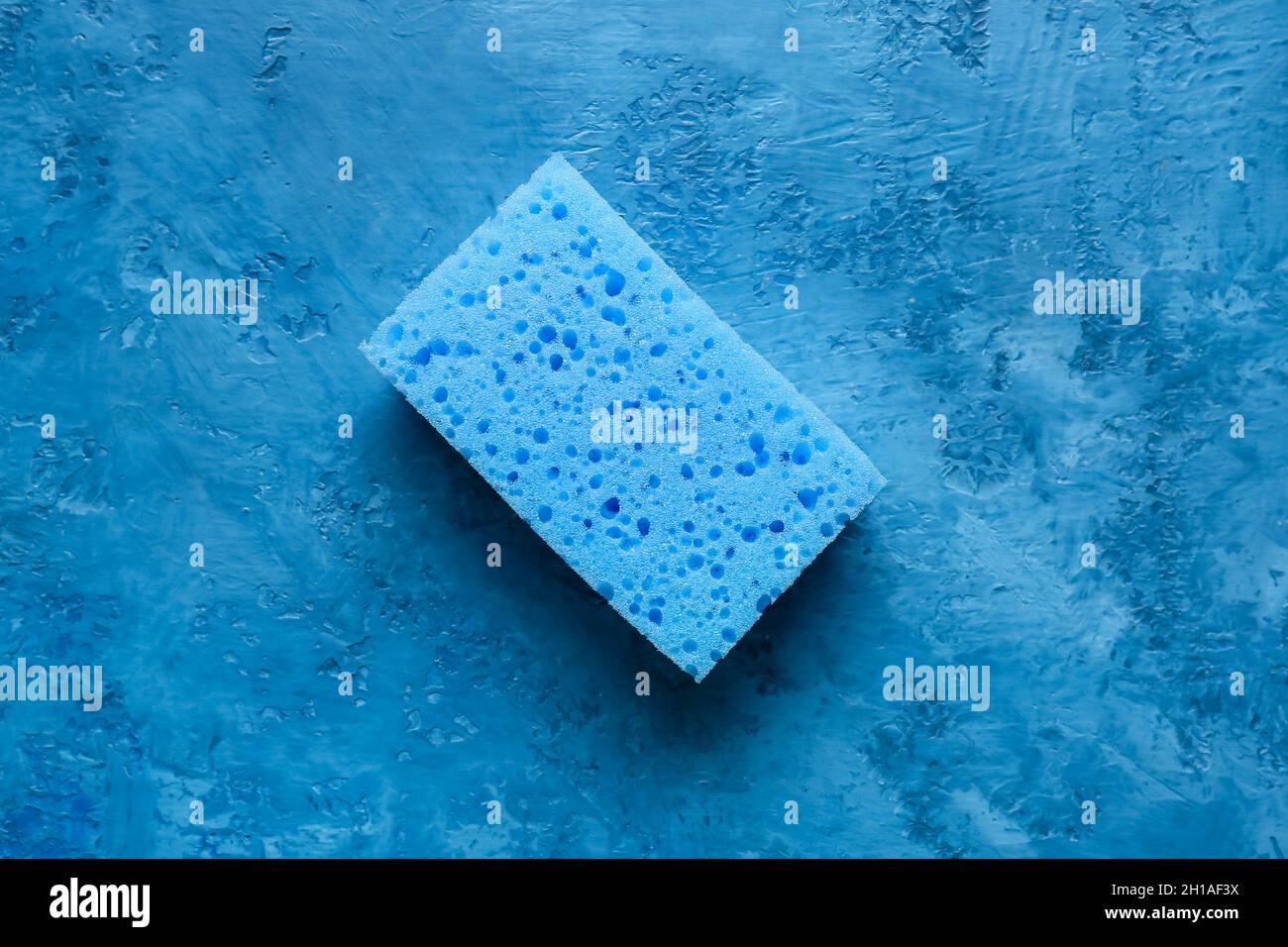 Blue cleaning sponge on color background Stock Photo - Alamy