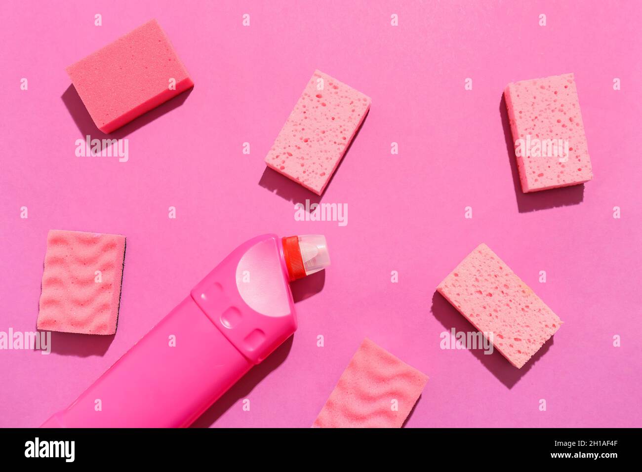 Pink cleaning sponges and bottle of detergent on color background Stock ...
