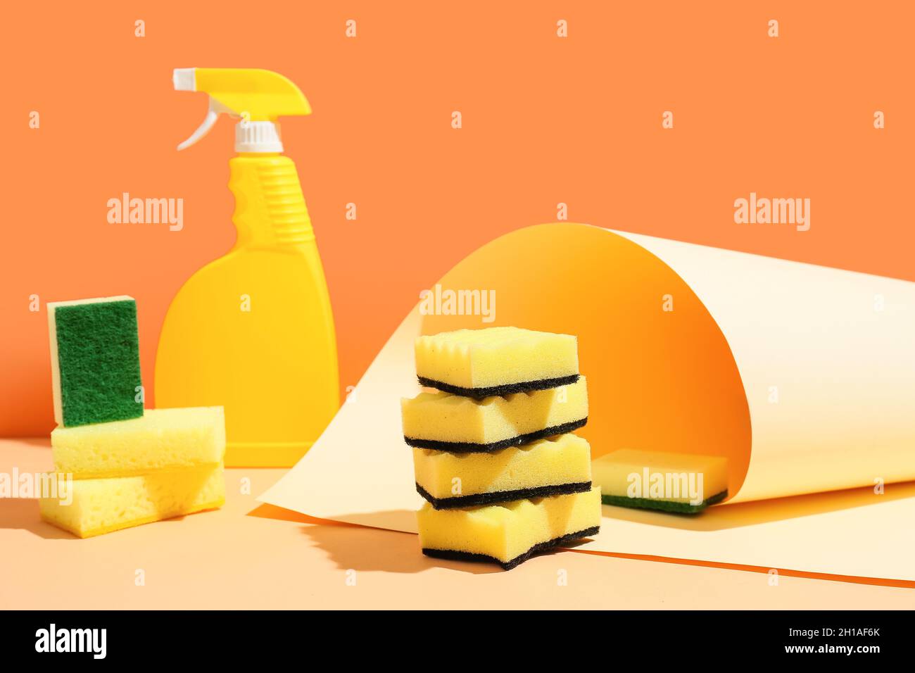 Yellow cleaning sponges and bottle of detergent on color background ...