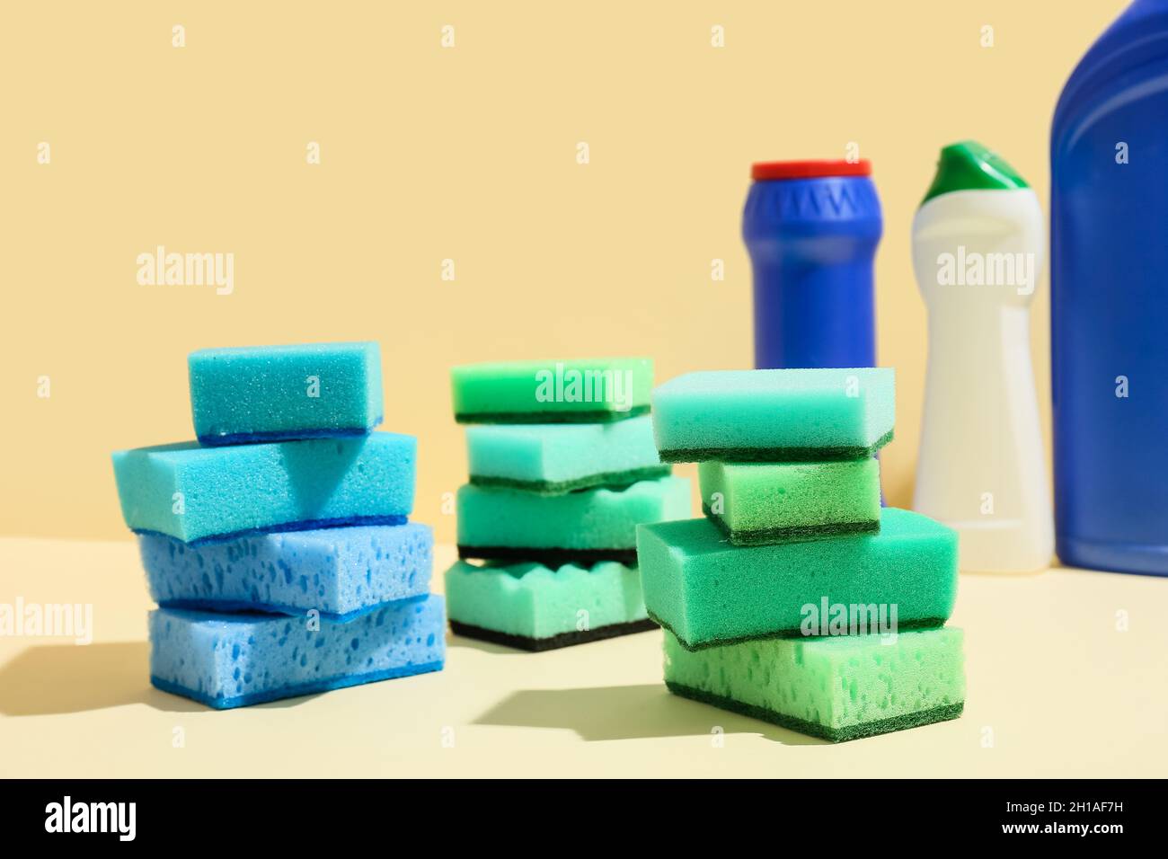 Different cleaning sponges and bottles of detergent on color background ...
