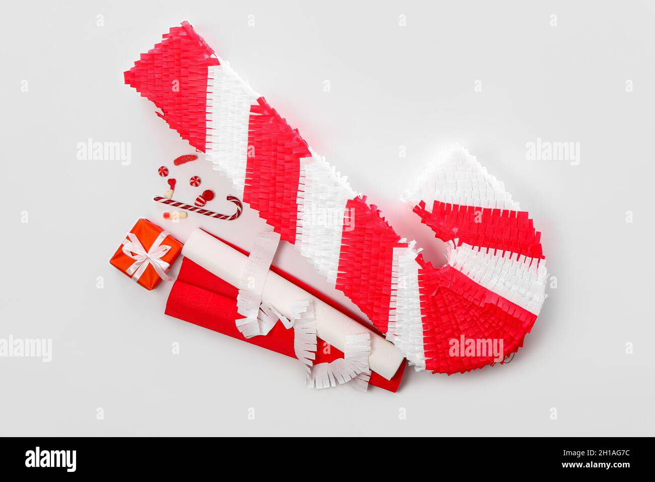 Mexican pinata in shape of cane with candies and gift on white ...