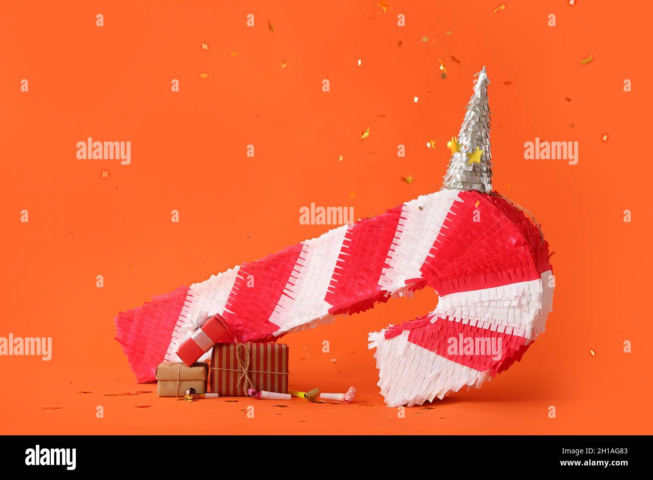 Mexican pinata in shape of cane with party hat and gifts on color ...