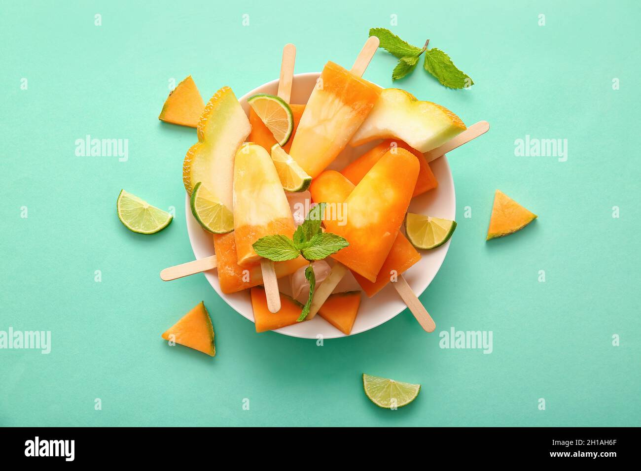 Plate with tasty melon popsicles on color background Stock Photo - Alamy