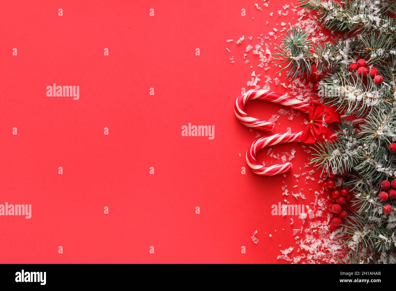 Composition with fir branches, berries, candy canes and snow on red ...