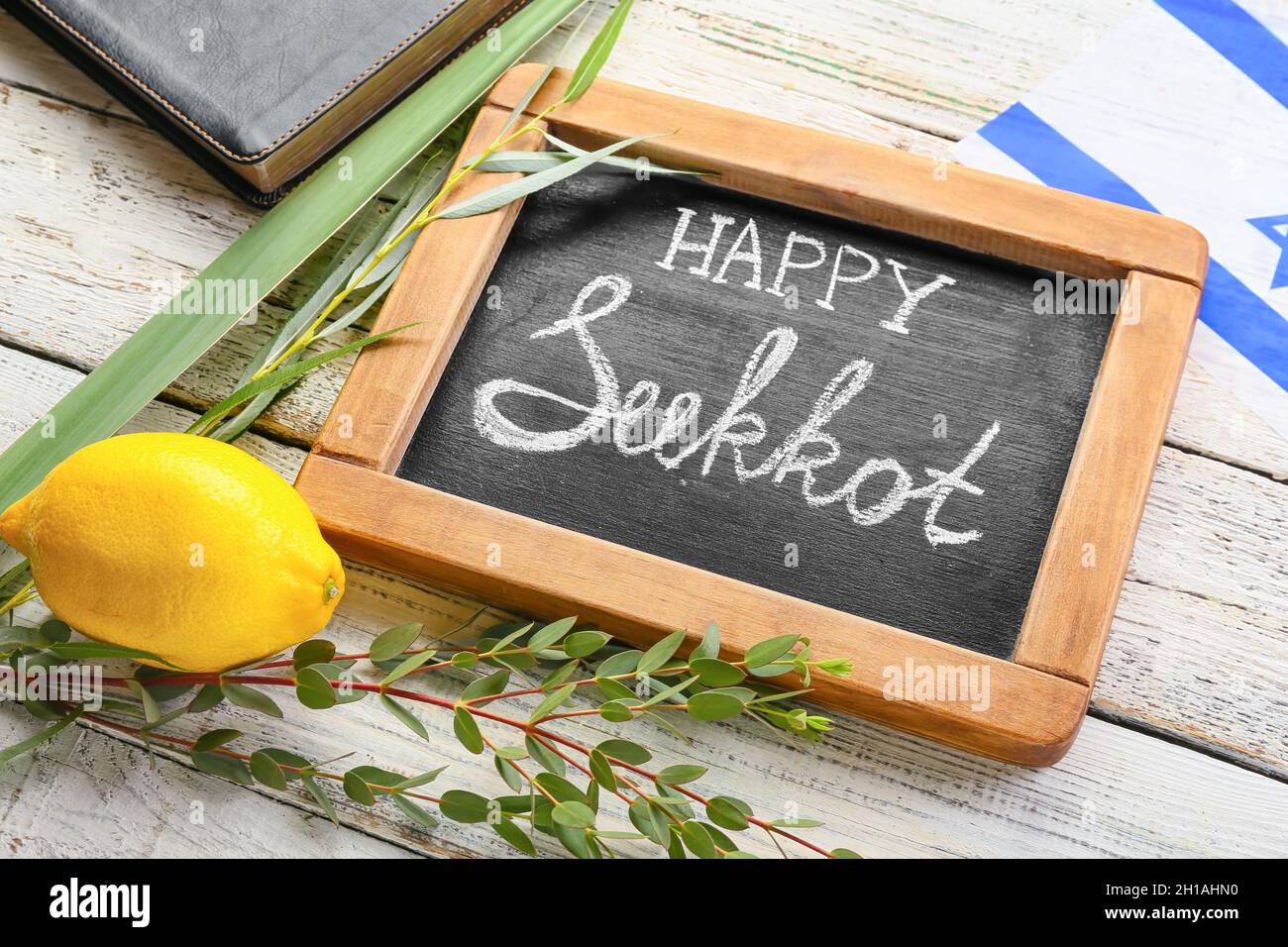 Chalkboard with text HAPPY SUKKOT and festival symbols on light wooden ...