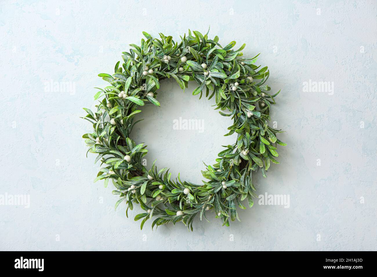 Simple mistletoe wreath on light wall Stock Photo - Alamy