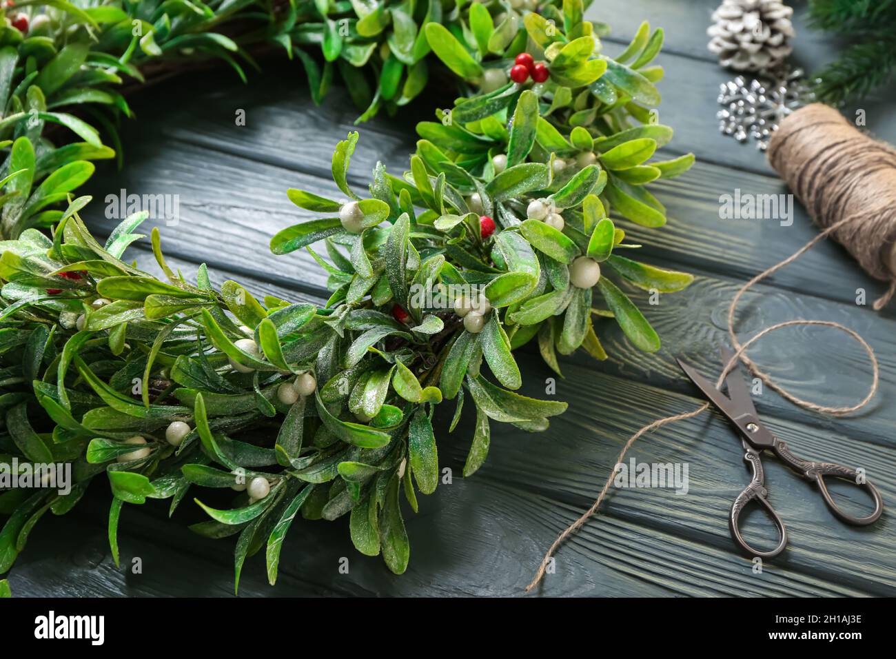 Beautiful mistletoe wreath and scissors on dark wooden background Stock ...