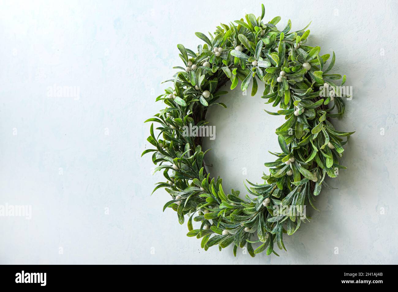 Simple mistletoe wreath on light wall Stock Photo - Alamy