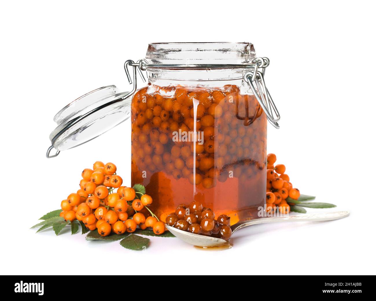 Glass jar and spoon with tasty rowan jam on white background Stock ...