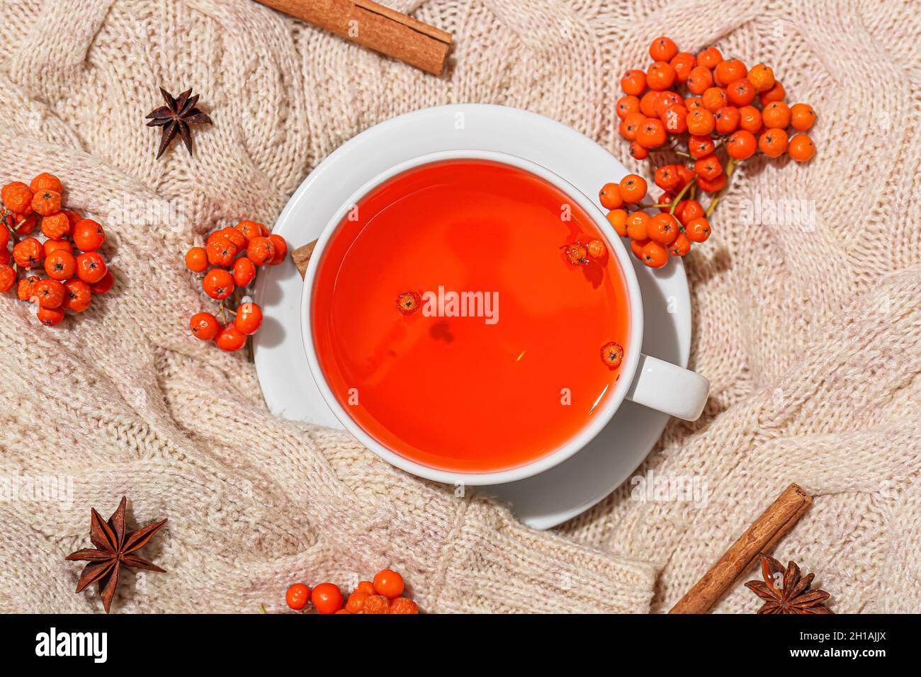 Composition with cup of tasty rowan tea, berries and spices on fabric ...
