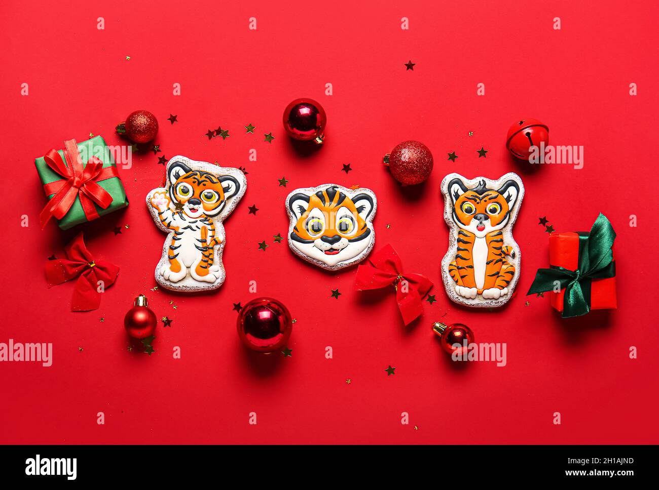 Tasty cookies in shape of tigers and Christmas decorations on red ...