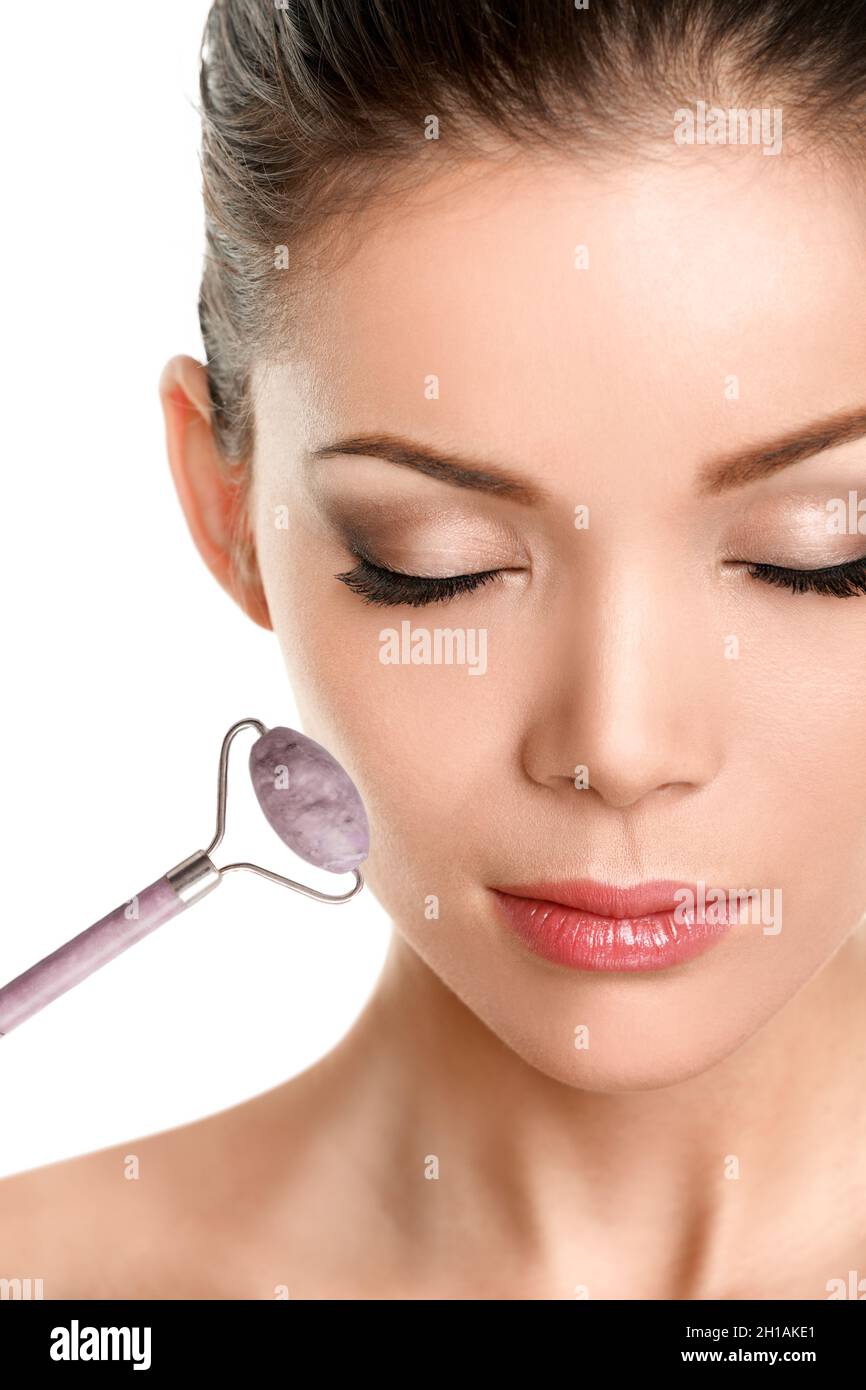 Asian beauty woman relaxing massaging face with jade face roller facial ...