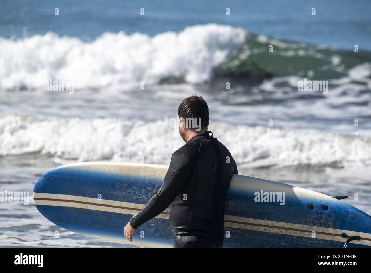 Side view of a man holding a surfboard by Ventura Beach Stock Photo - Alamy