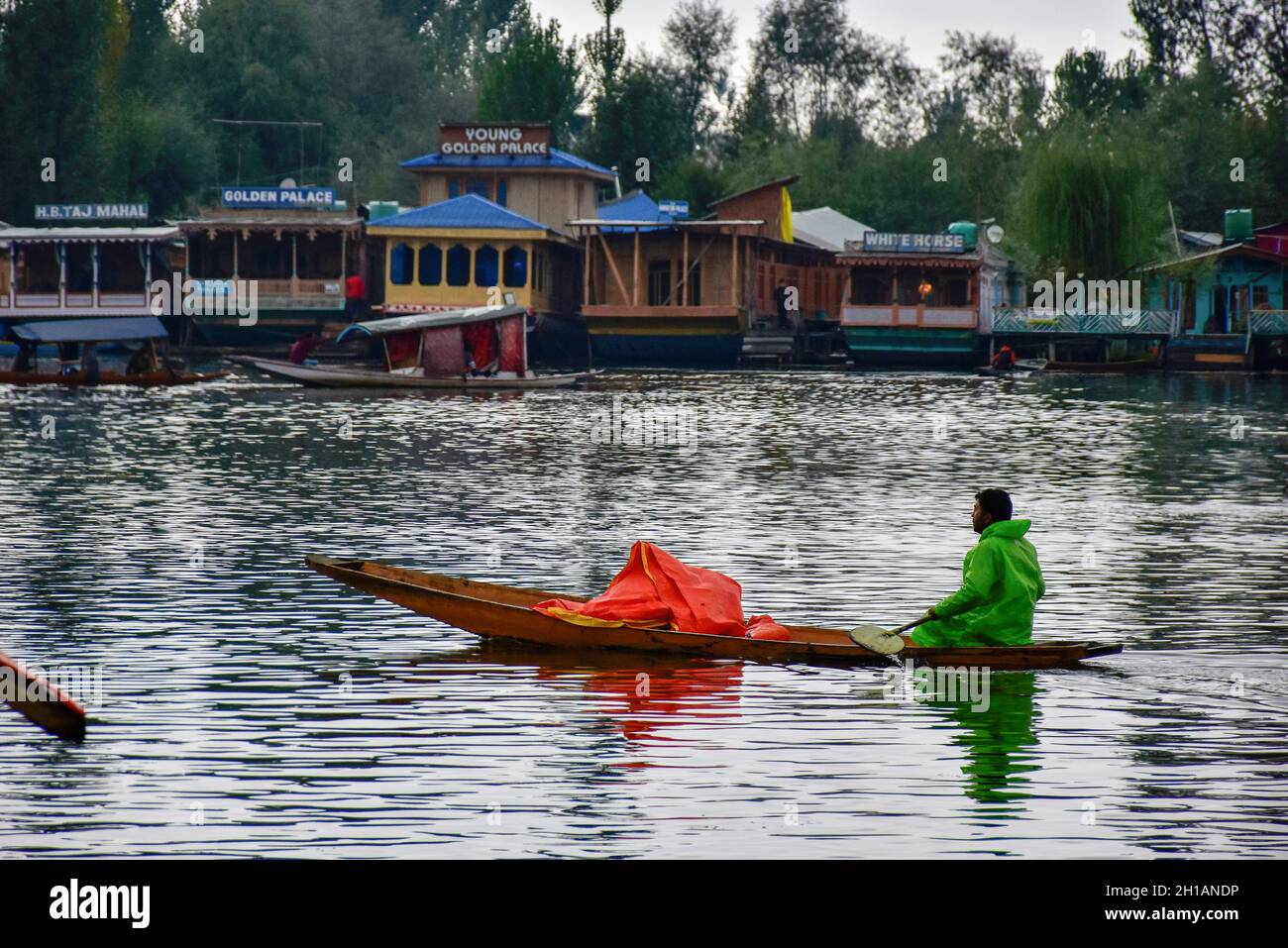 Srinagar, India. 17th Oct, 2021. A boatman wears a rain jacket as he ...