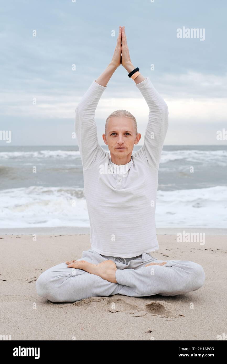 Man doing yoga on the beach in autumn over waves in the sea. Creamy ...