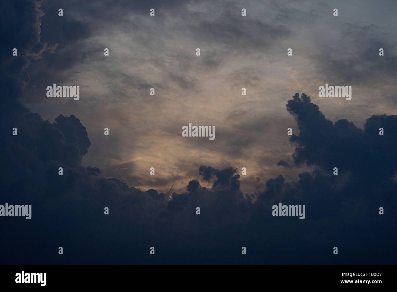 Dark clouds with dimmed sun lights in the background at dusk. Selective ...