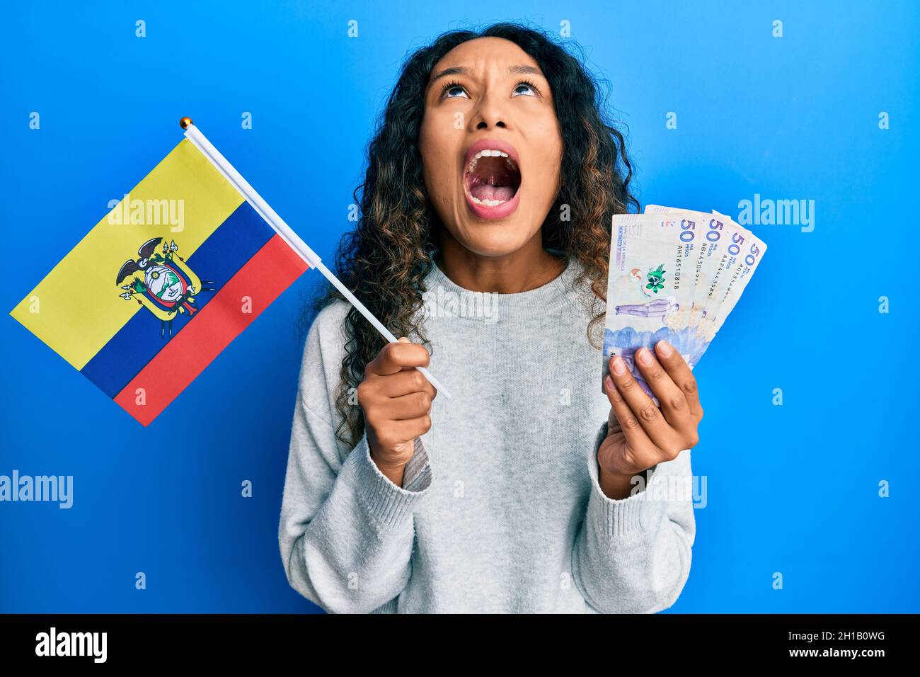 Young latin woman holding colombia flag and colombian pesos banknotes ...
