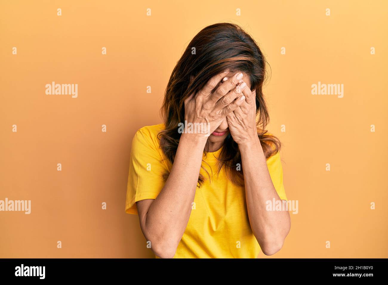 Young latin woman wearing casual clothes with sad expression covering ...