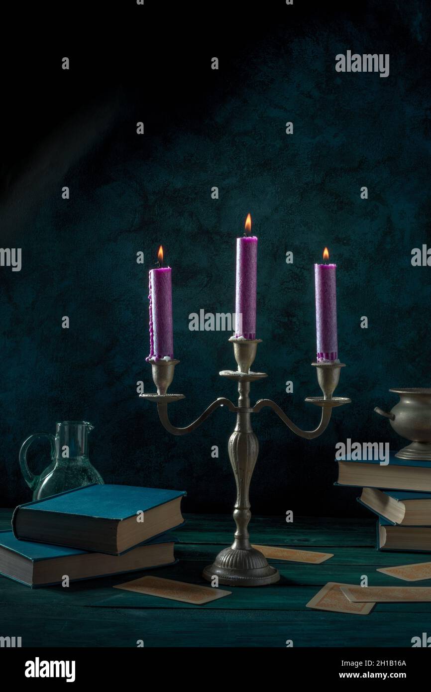 Candle magic. Purple candles and occult books on a dark background with ...