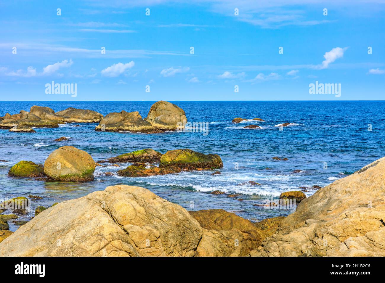 Rock on the beach with beautiful clouds in tropical sea Stock Photo - Alamy