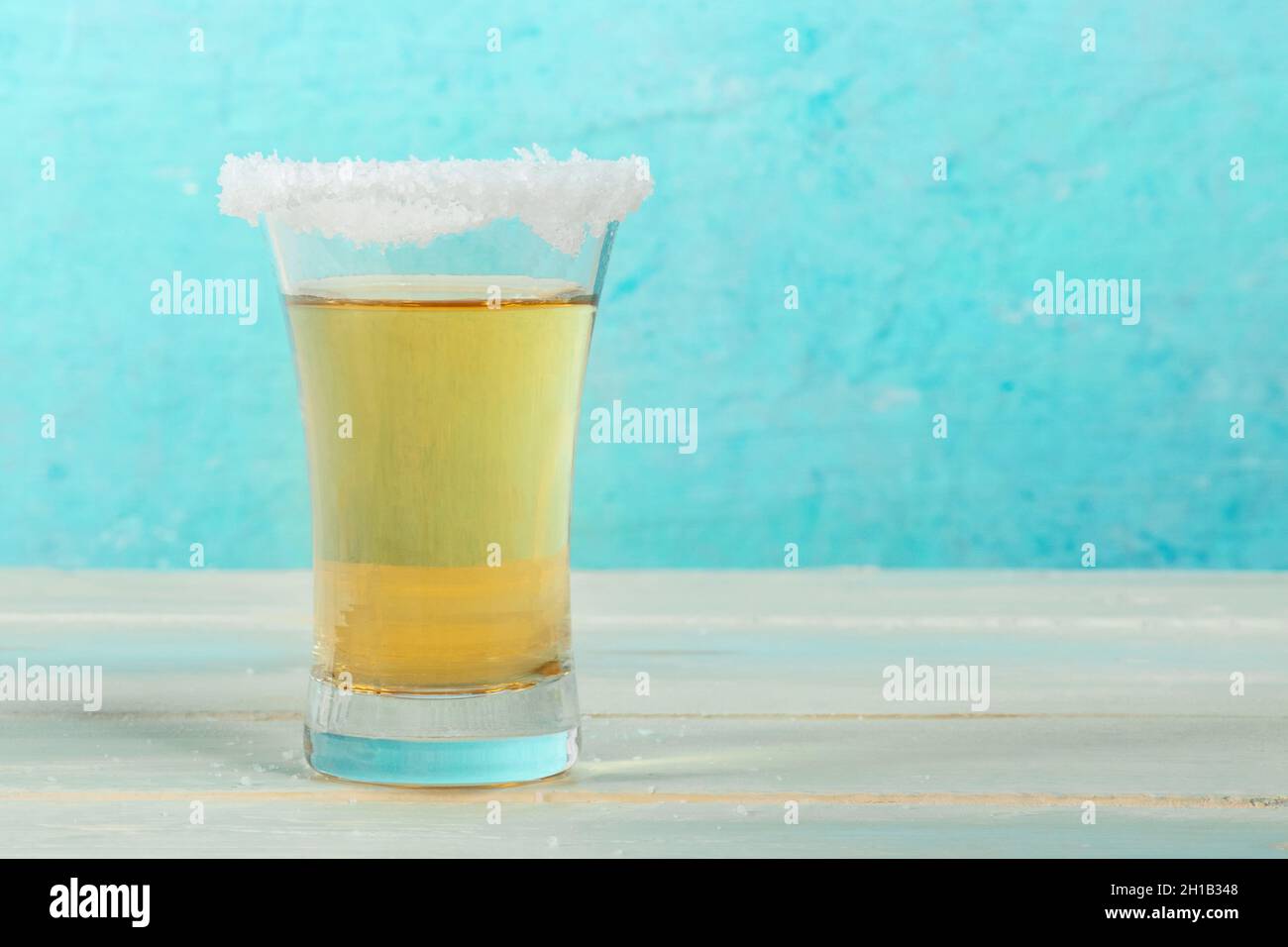 Gold tequila shot, a traditional Mexican drink on a teal blue ...