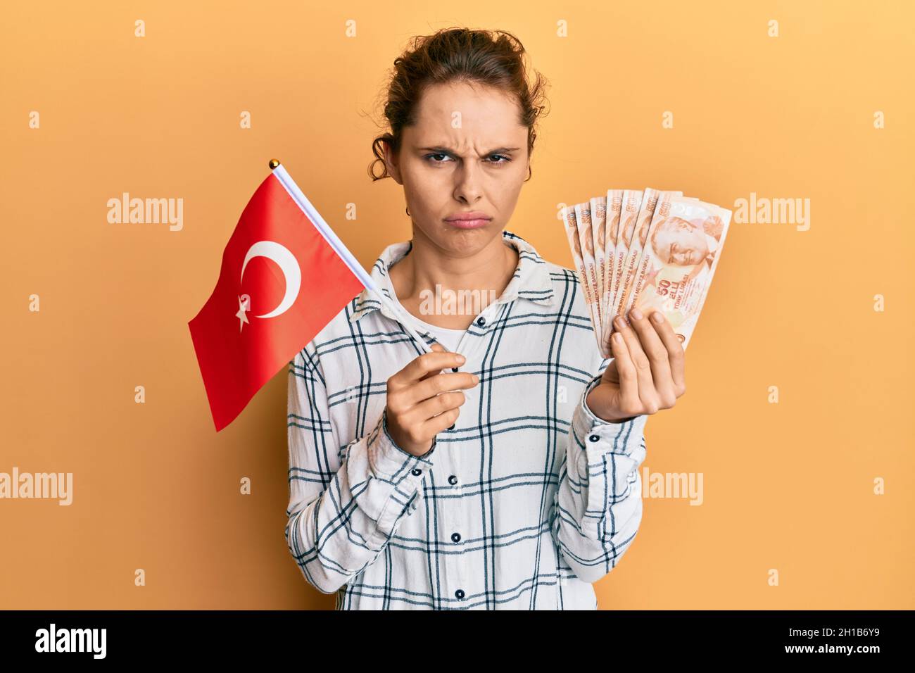 Young brunette woman holding turkey flag and liras banknotes depressed ...