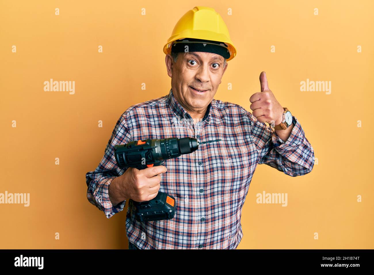 Handsome senior man with grey hair holding screwdriver wearing hardhat ...