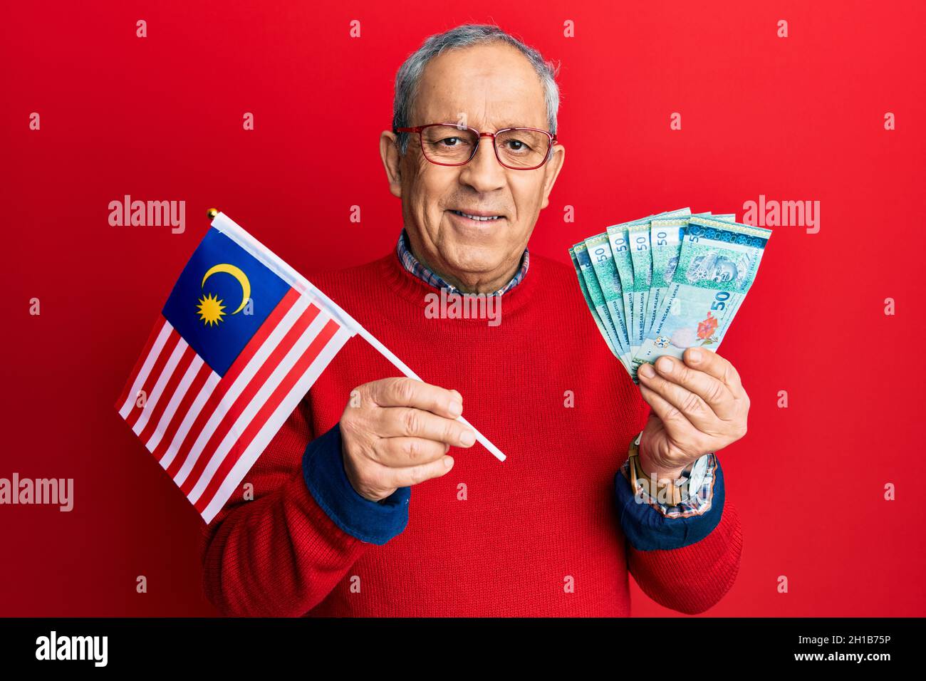 Handsome senior man with grey hair holding malaysia flag and malaysian ...