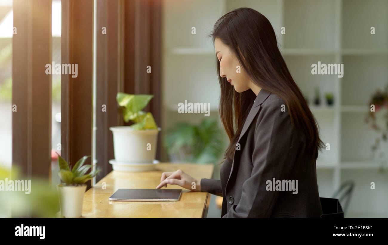 Side view of a female freelancer in casual suit checking her banking ...
