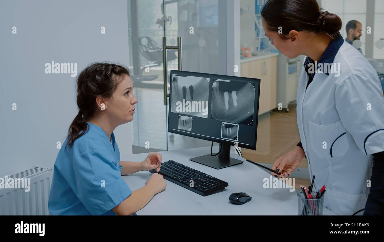 Stomatologist and nurse examining dental x ray scan on computer monitor ...