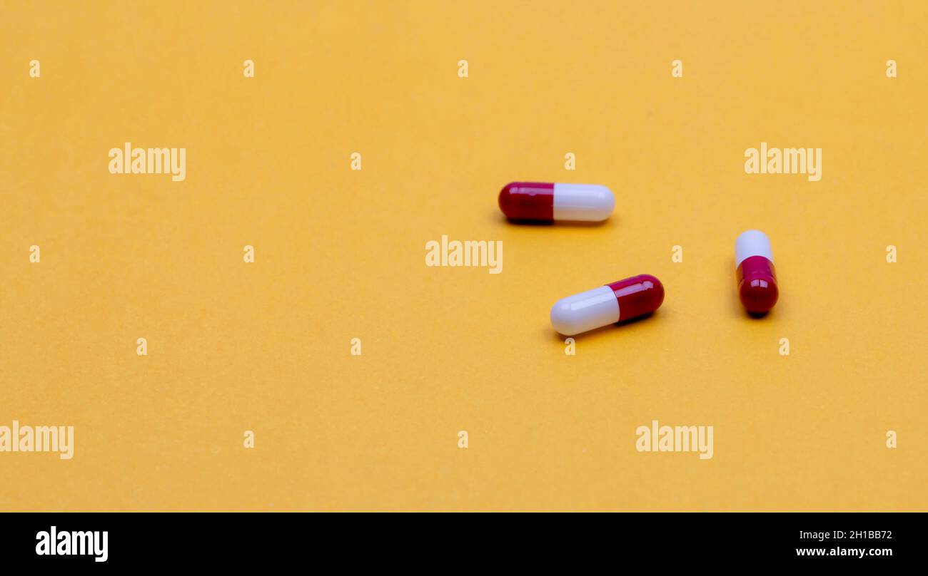 Red-white antibiotic capsule pills on yellow background. Prescription ...