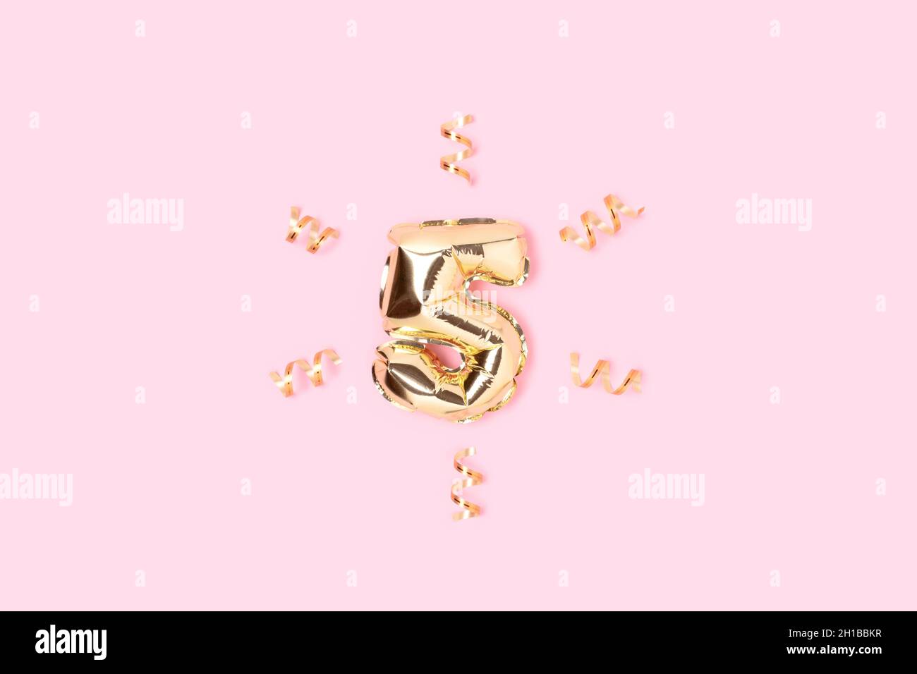 Number 5 golden air balloon with confetti on a pink pastel background ...