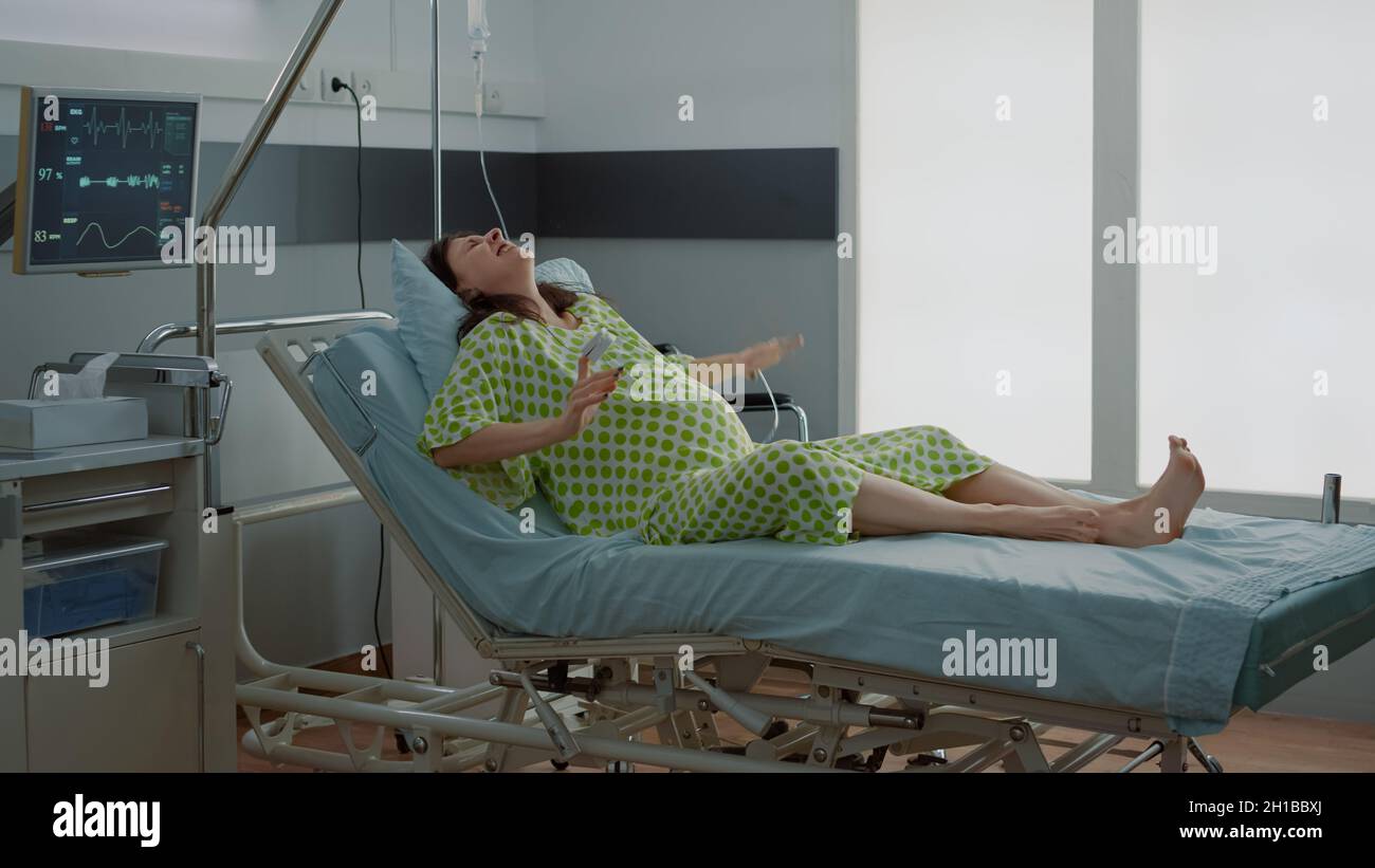 African american nurse helping pregnant woman with painful contractions ...