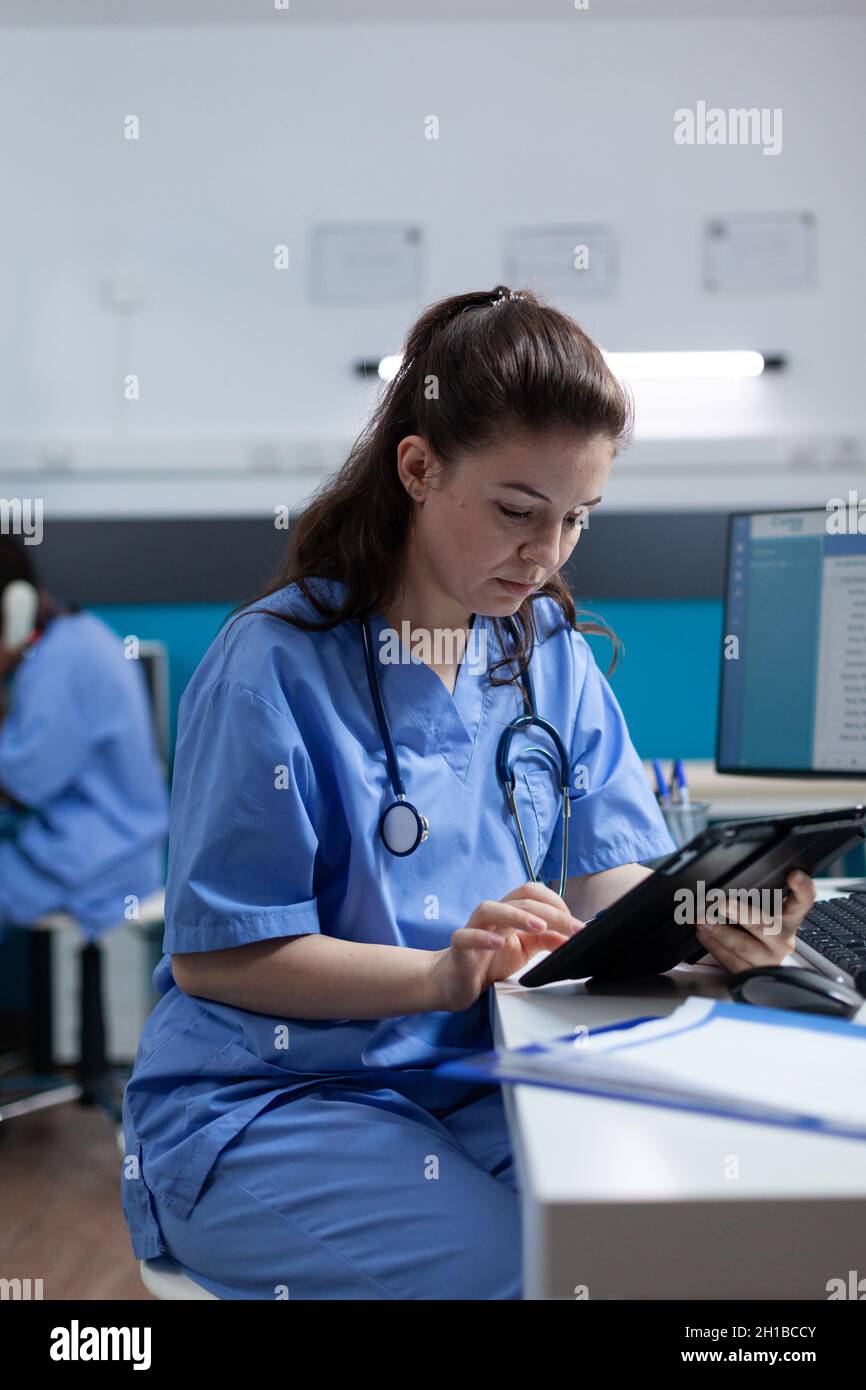 Pharmacist nurse looking at tablet computer analyzing sickness ...