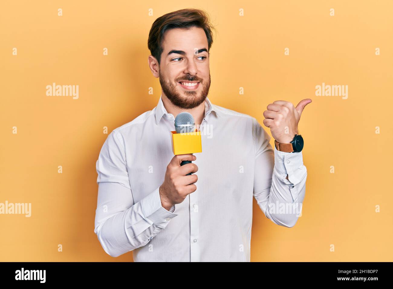 Handsome caucasian man with beard holding reporter microphone pointing ...