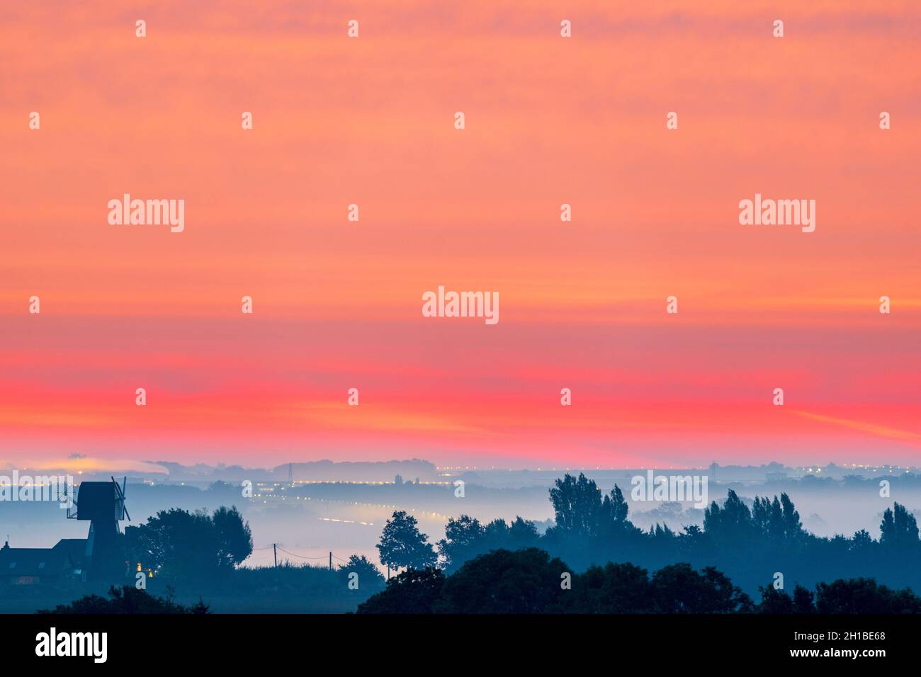 Red dawn sky over a mist covered Kent Landscape with some trees and a ...