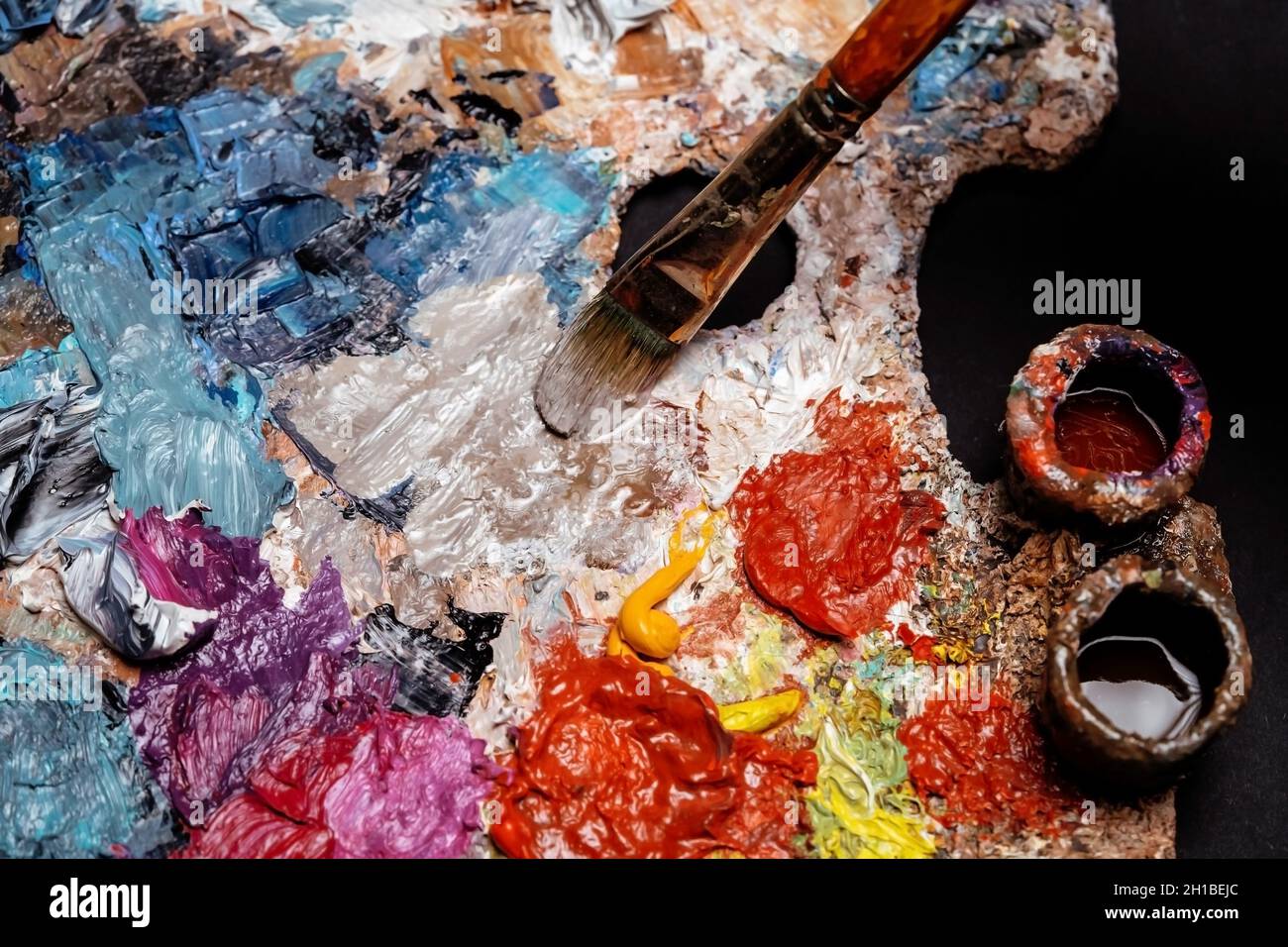 Brush mixing bright colors from relief layers of oil paints Stock Photo ...