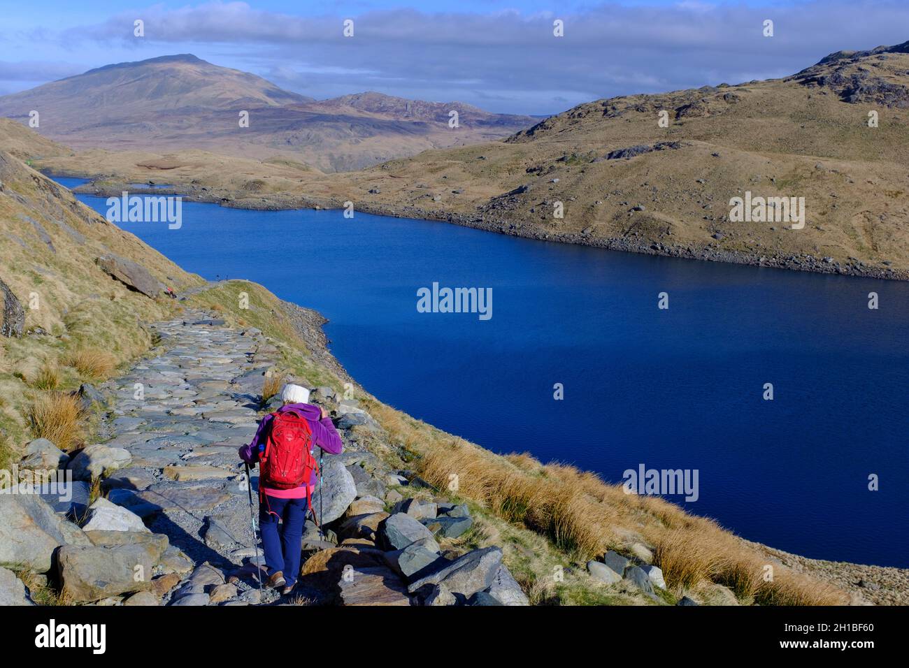 A woman with a red backpack hiking down the Miners track in Snowdonia ...