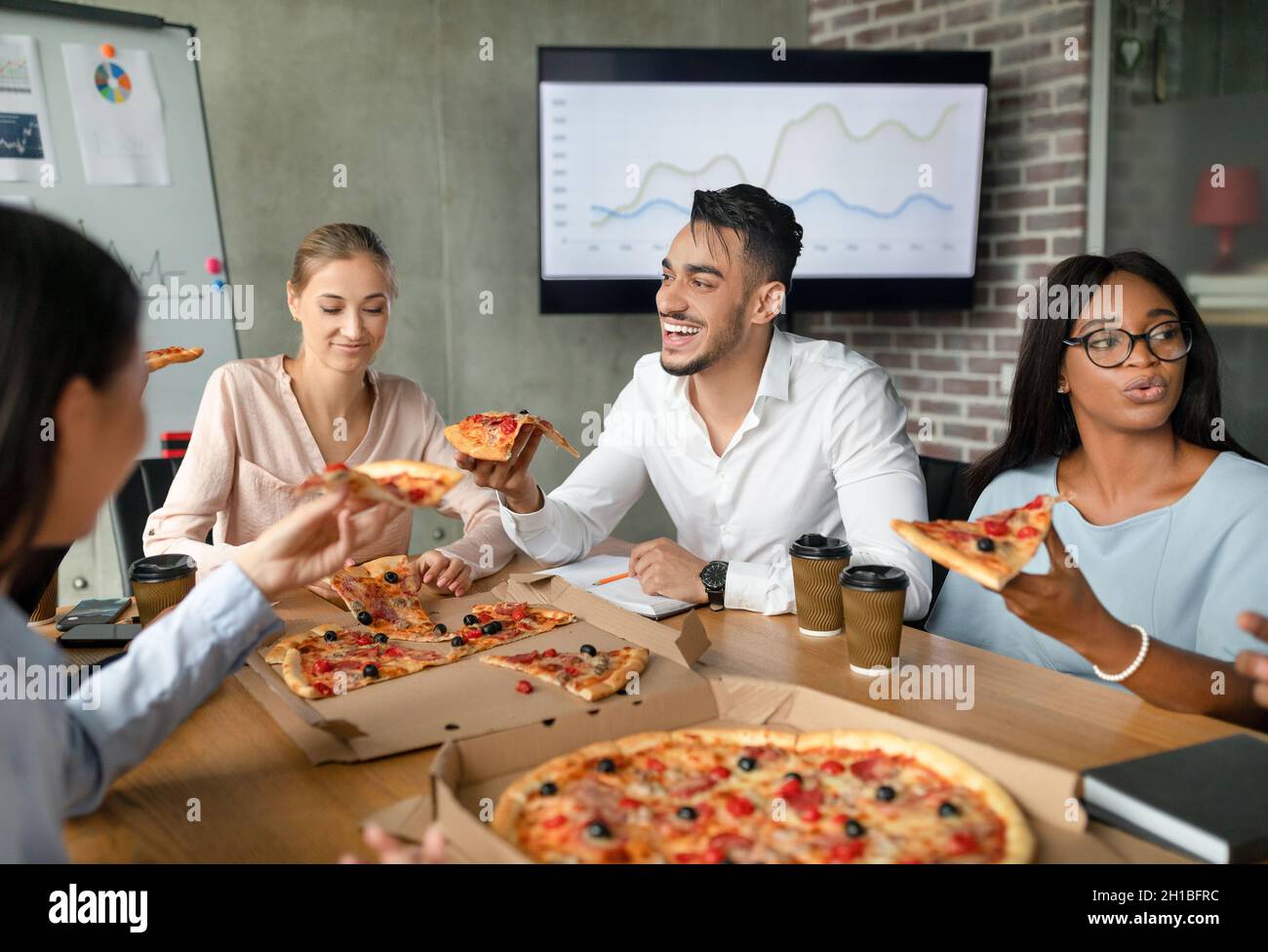 Diverse Multiethnic Colleagues Eating Pizza During Lunch Break In