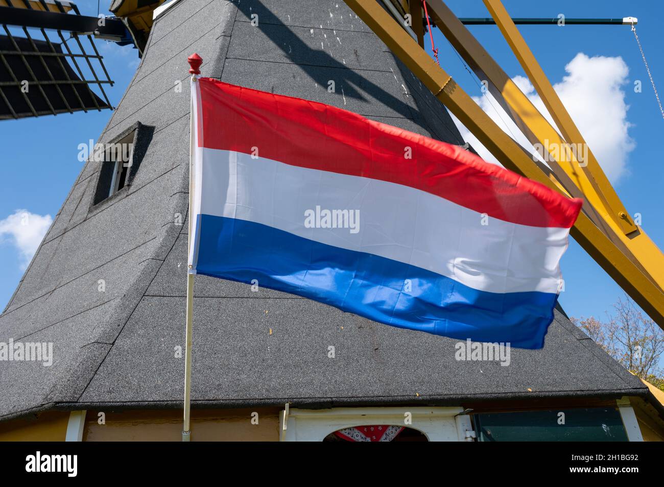 Dutch flag and old traditional windmill used for grain grinding on ...